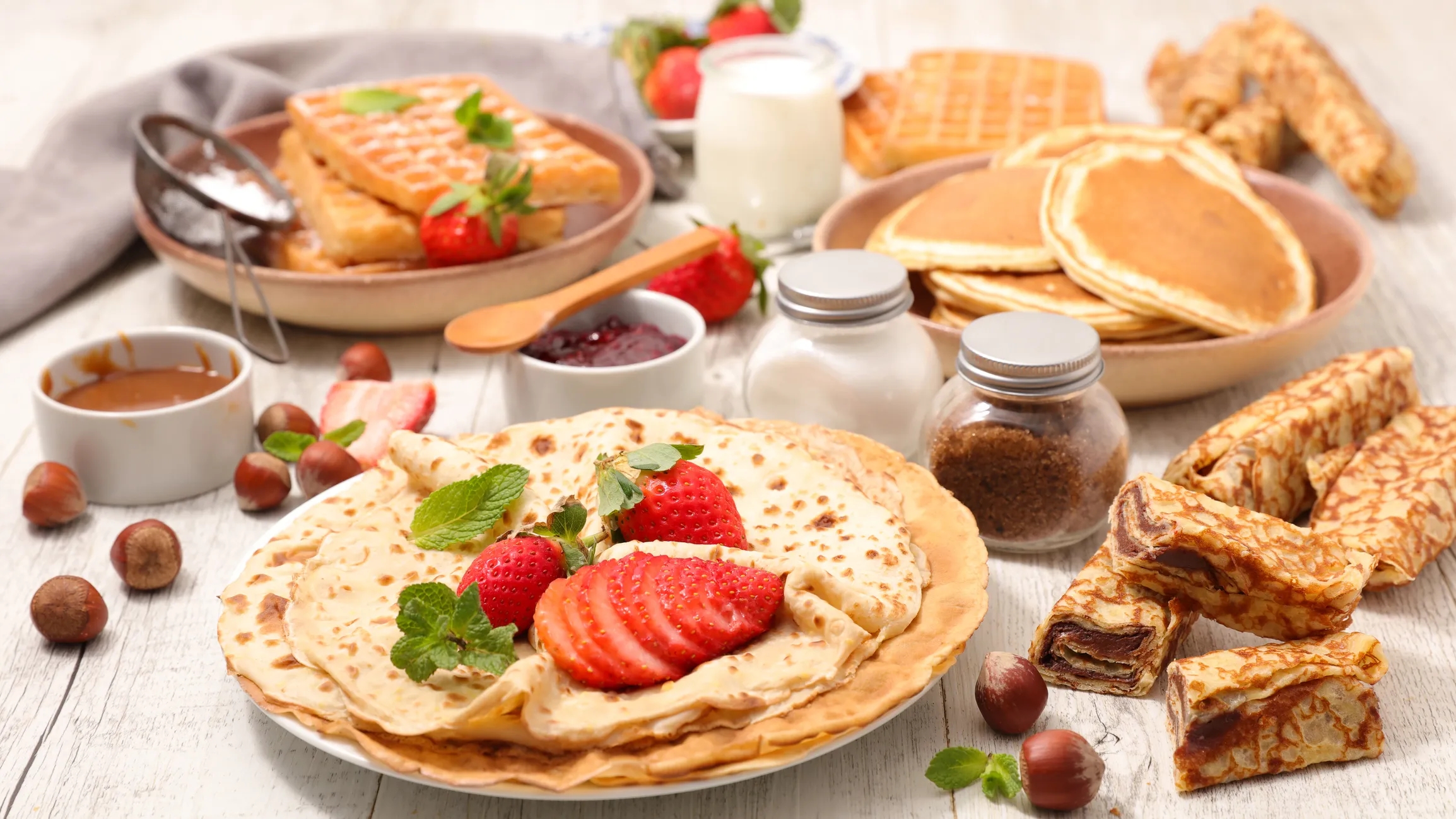 Various crepes, pancakes, andwaffles topped with fruit and chocolate ...